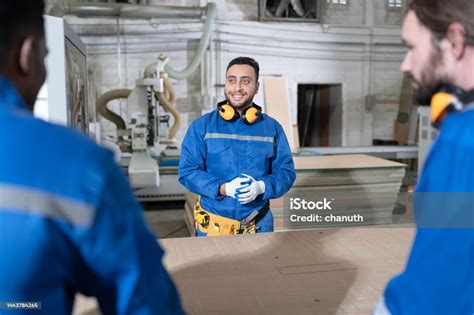 행복 한 잘 생긴 목수 남자와 팀 믹스 레이스 안전 파란색 유니폼 작업 나무 공장에서 기계 배경 20 24세에 대한 스톡 사진