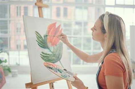 이젤과 색상을 사용하여 캔버스에 그림을 그리는 스튜디오나 작업장에서 여성과 함께 꽃 페인트 예술 또는 창작 수채화 식물 예술적인