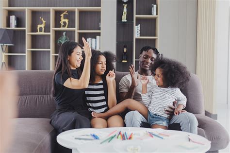 젊은 아시아계 미국인 가족 부모와 어린 딸이 집에서 함께 그림을 그립니다 아시아계 미국인 가족과 아빠가 거실에서 아이와 함께 그림을 그리고 연필을 사용하고 재미 있고