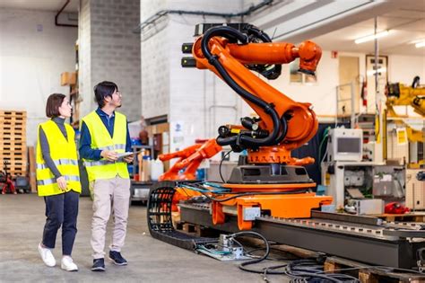 Premium Photo Two Multiethnic Engineers Walking Into The Factory Of Robotic Arms Production