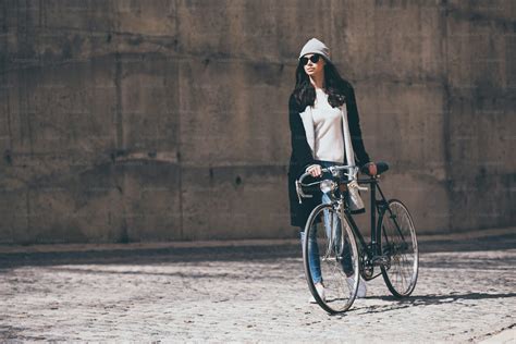 선글라스를 낀 아름다운 젊은 여성이 자전거를 굴리고 야외를 걷는 동안 시선을 돌린다 사진 Unsplash의 빈 표현식 이미지