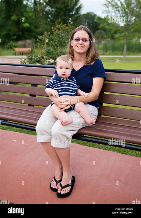 Mother And Son Sitting On A Park Bench At An Outdoor Park Playground
