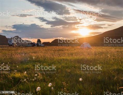 하얀 꽃과 텐트가있는 캠프장 지역의 Landmannalaugar 산의 아름다운 오렌지색 일출 아이슬란드의 하이랜드 지역의 Fjallabak 자연 보호 구역 0명에 대한 스톡