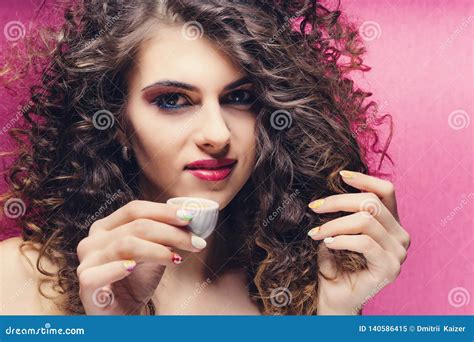 Bella Ragazza Riccia Con Il Manicure Colourful Che Beve Da Una Tazza