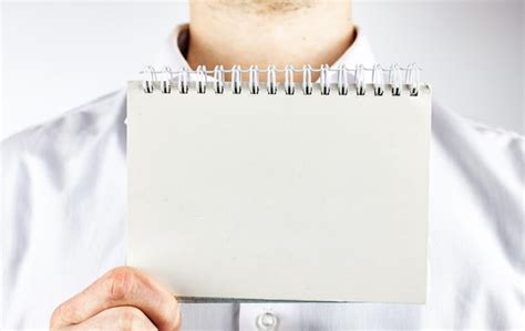 Premium Photo A Man In A White Shirt Holds A Notebook With A Blank Sheet Form Blank For