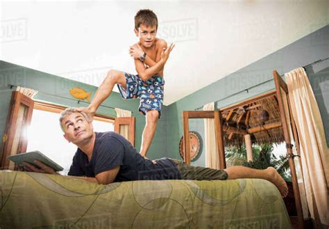 Boy Standing On Father On Bed Stock Photo Dissolve