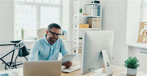 디지털 태블릿을 사용하고 사무실에 앉아 웃고 있는 스마트 캐주얼 옷을 입은 잘생긴 중년 남자 사진 Unsplash의 우크라이나 이미지