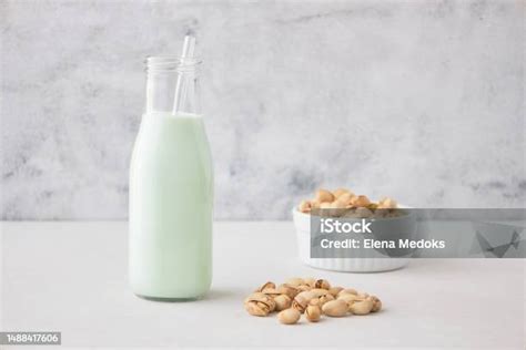 피스타치오 옆의 회색 테이블에 병에 담긴 피스타치오 우유 식물성 우유 채식주의자를 위한 견과류 우유 0명에 대한 스톡 사진 및 기타 이미지 Istock
