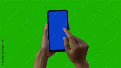 Phone in the hand close up isolated at green background. Phone screen is blue chroma key ...