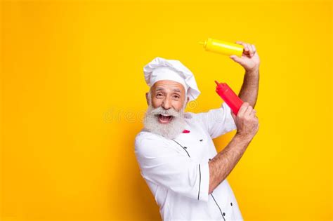 Cheerful Senior Chef In A Bright Uniform Posing With Condiment Bottles