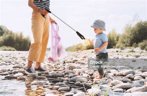 어머니는 놀고있는 유아 아들 근처의 쓰레기로 야외 공간을 청소합니다 자원 봉사자 가족은 강물에 플라스틱 쓰레기를 수거합니다 사람들은 자연을 깨끗하게 유지하고 쓰레기를 줍는