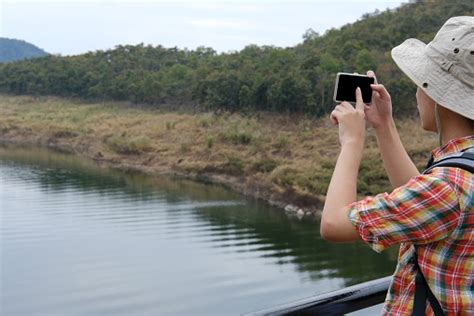 배낭 여행자 남자 숲 및 호수에서 여행 백 패 커 관광 스마트 휴대 전화를 사용 하 여 사진 라이프 스타일 여름 휴가 개념 강에
