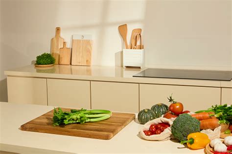 인덕션 쿠커 나무 도마와 같은 조리기구가 완비된 현대적인 주방 신선한 야채가 주방 카운터에 놓여 있습니다 셀러리를 가공할 준비가 되었습니다 0명에 대한 스톡 사진 및 기타