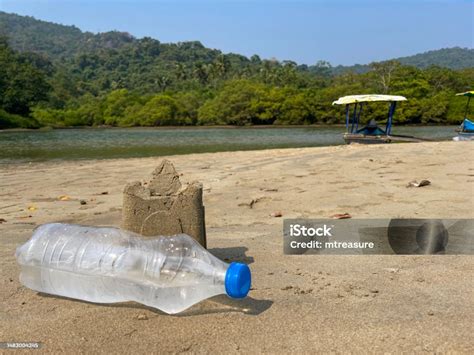 마른 모래 해변에 양동이와 삽으로 만든 모래성 외에 플라스틱 물병의 클로즈업 이미지 해안의 바다 쓰레기와 오염 모래 낚시 보트 야자수가 있는 삼림 지대 전경에 초점 30