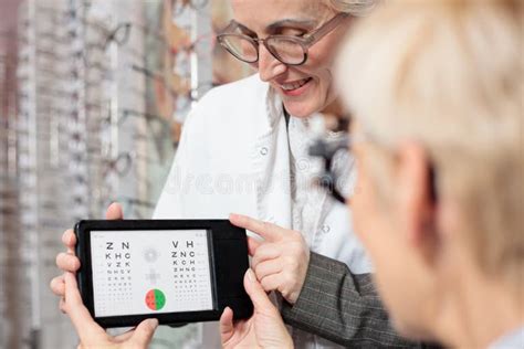 Smiling Mature Female Ophthalmologist Testing Patient`s Vision For