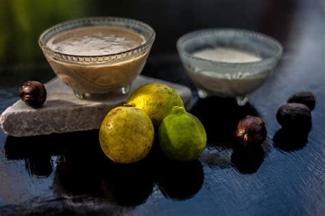 일부 육두구 분말 요구르트와 유리 그릇에 잘 혼합 일부 레몬 주스의 흐릿한 배경 Consisiitng와 나무 표면에 향신료 얼굴 마스크 원시 육두구 얼굴 마스크와 레몬