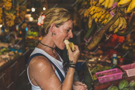 Premium Photo Side View Of Mature Woman Eating Banana At Market