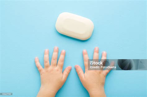 밝은 파란색 테이블 배경에 아기 소년 손과 흰색 자연 비누 파스텔 색상 근접 촬영 관점 샷 깨끗하고 부드러운 바디 스킨에 신경을 쓰다 매일 어린이 위생 하향 보기 아기에