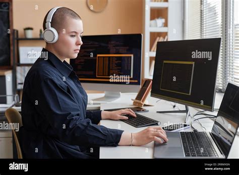 portrait of female programmer wearing headphones and using computer