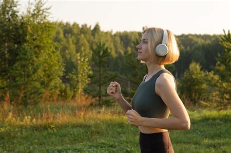 야외에서 조깅하는 동안 음악을 듣는 젊은 여자 여름 공원에서 이른 아침에 운동하는 마른 소녀 Brand Name Smart Phone에 대한 스톡 사진 및 기타 이미지