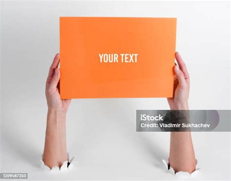 흰색 배경의 찢어진 구멍을 통해 복사 공간을 위해 주황색 종이를 들고있는 여성의 손 크리에이티브 아트 개념에 대한 스톡 사진 및 기타 이미지 Istock
