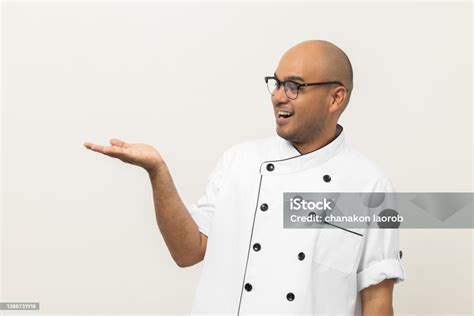 미소 짓는 젊은 잘 생긴 아시아 남자 요리사는 안경을 착용하고 서있는 채로 손바닥을 들고 고립 된 메뉴를 들고 게시합니다 요리