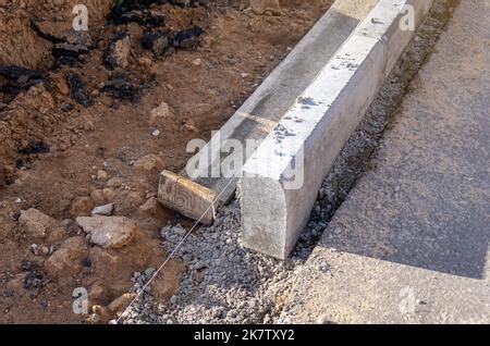 Concrete curbs installation works at road construction site. String ...