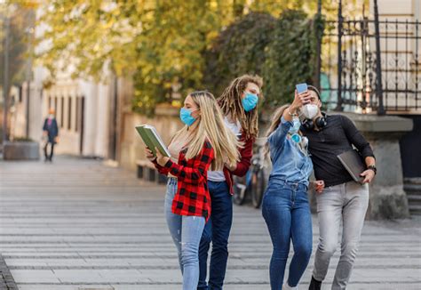 4명의 학생이 보호용 얼굴 마스크를 들고 도시 지구를 걷고 있습니다 20 24세에 대한 스톡 사진 및 기타 이미지 20 24세 20 29세 25 29세 Istock