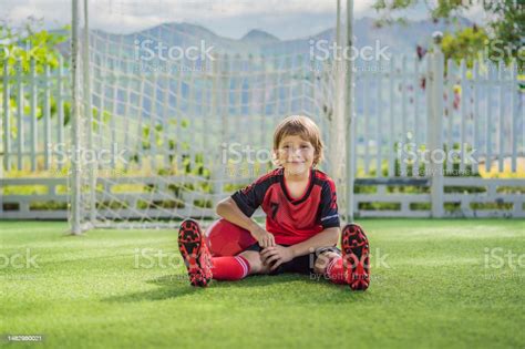 빨간 축구 유니폼을 입은 귀여운 소년이 야외에서 축구 축구를 하고 있다 아이들이나 아빠와 함께 스포츠를 하는 활동적인 아이