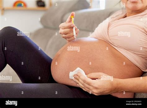 mature pregnant woman puting injection on her belly at home woman on