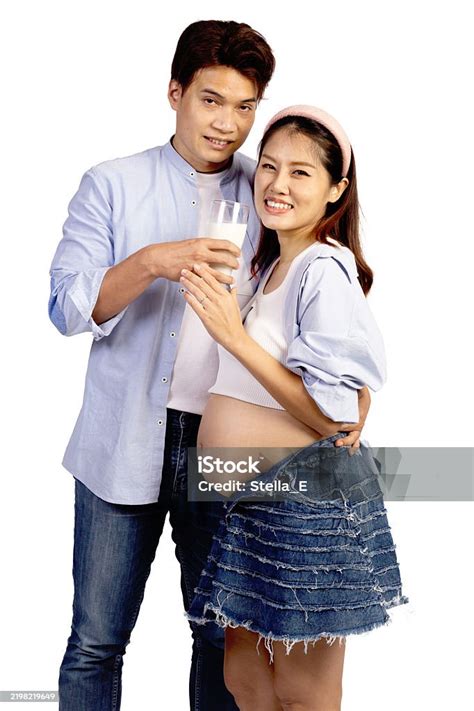 흰색 배경에 행복한 가족 아시아 커플 남편은 임신한 아름다운 아내에게 우유잔을 건네며 포옹한다 뱃속에 있는 아기를 위해 풍부한 칼슘 음식을 마시는 큰 배를 가진 임신 엄마