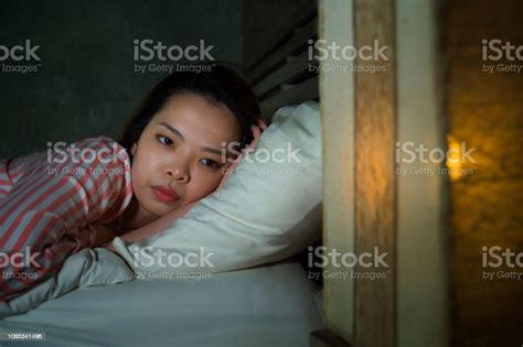 Young Beautiful Sad And Depressed Asian Chinese Girl Lying On Bed Late ...