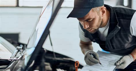 자동차 정비소에서 일하면서 자동차 오일을 확인하고 메모하는 젊은 정비사 사진 Unsplash의 기술자 이미지