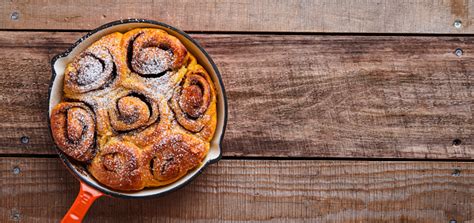 호박 너트 캐러멜 슈가 크림을 곁들인 시나본 계피 롤빵이 소박한 나무 배경 테이블에 장식되어 있습니다 맨 위 보기입니다 달콤한 홈메이드 페이스트리 크리스마스 베이킹 카넬불레