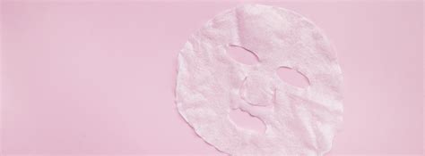 파스텔 핑크 종이 배경에 시트 얼굴 마스크입니다 웹 디자인 배너 스킨 케어 피부과 뷰티 컨셉 상단 보기 플랫 레이 모형 오버 헤드 복사 공간 템플릿 0명에 대한 스톡 사진