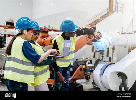 multiracial engineers working with robot arm at robotic warehouse
