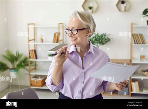Senior Business Woman Talking On Speaker Phone Recording Voice Message