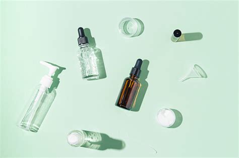 밝은 녹색 배경에 어둡고 투명한 유리로 만든 화장품에 대한 빈 병의 모형 바디 앤 페이스 트리트먼트 와 스파 천연 미용 제품 마사지 오일 공간을 복사합니다 플랫 레이 개념에