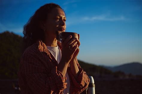 고요한 풍경 속에서 체크무늬 셔츠를 입고 보온병 컵을 들고 평화로운 표정으로 일출 야외에서 따뜻한 음료를 즐기는 여성 40 44세에 대한 스톡 사진 및 기타 이미지 Istock