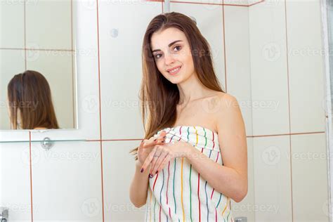 Smiling Young Girl Standing In A Towel In A Bathroom Near The Mirrors