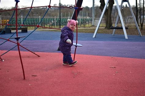 추운 날씨의 봄에 도시 공원의 어린이 놀이터에서 웃고 노는 아기 소녀 겨울에 공공 놀이터에서 즐거운 시간을 보내는 유아 소녀 12 17 개월에 대한 스톡 사진 및 기타