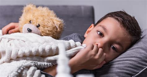 질병 계절성 바이러스 문제 개념 독감에 걸린 소년이 소파에 누워 온도계의 온도를 보고 있다 아픈 아이는 고열로 침대에 누워 있습니다 감기 독감과 편두통 사진