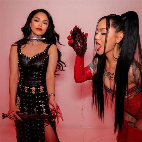 Two Women Dressed Up In Costumes And One Is Holding A Heart Shaped Object With Both Hands