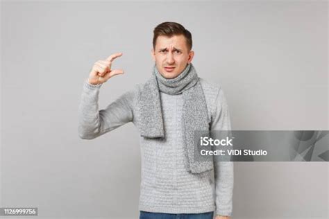 회색 스웨터에 우려 남자 스카프 회색 벽 배경에서 분리 하는 작업 크기를 보여주는 몸짓 건강 한 라이프 스타일 사람들이 진심으