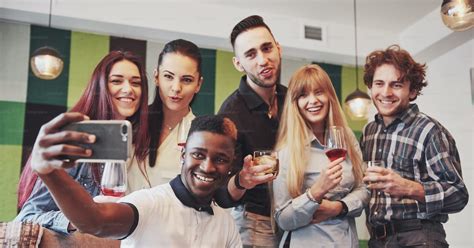 레스토랑에서 즐거운 시간을 보내는 친구들 세 명의 소년과 세 명의 소녀가 셀카를 만들고 웃고 있습니다 스마트폰을 들고 있는