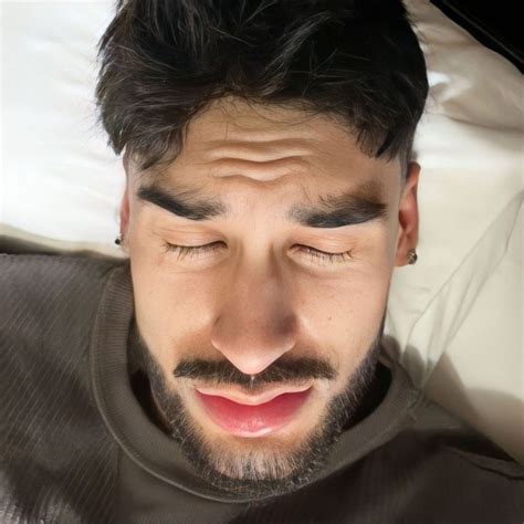 A Man Laying In Bed With His Eyes Closed And One Eye Opened To The Side