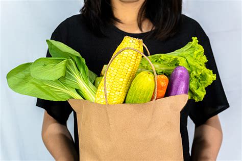 아시아 여자는 채식주의자를위한 주식으로 다양한 신선한 야채와 종이 봉지를 가져 온다 고립 된 흰색 배경 세계 완전 채식주의 자의 날 개념 가방에 대한 스톡 사진 및 기타