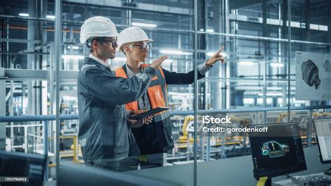 남성 엔지니어와 여성 산업 제품 디자이너가 자동차 조립 공장에서 사무실에서 태블릿을 사용하는 동안 작업에 대해 논의합니다 기술 공장에서 차량 설계작업을 담당하는 산업 전문가