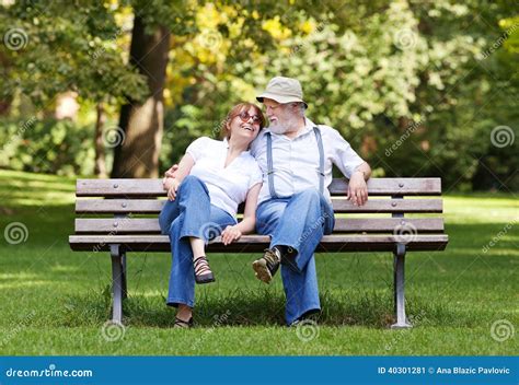 Старшие пары сидя на скамейке в парке Стоковое Изображение изображение насчитывающей люди