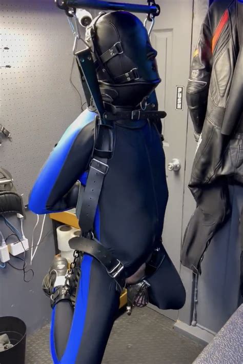 Gimp Of Lycra And Leather Suspended In Chastity